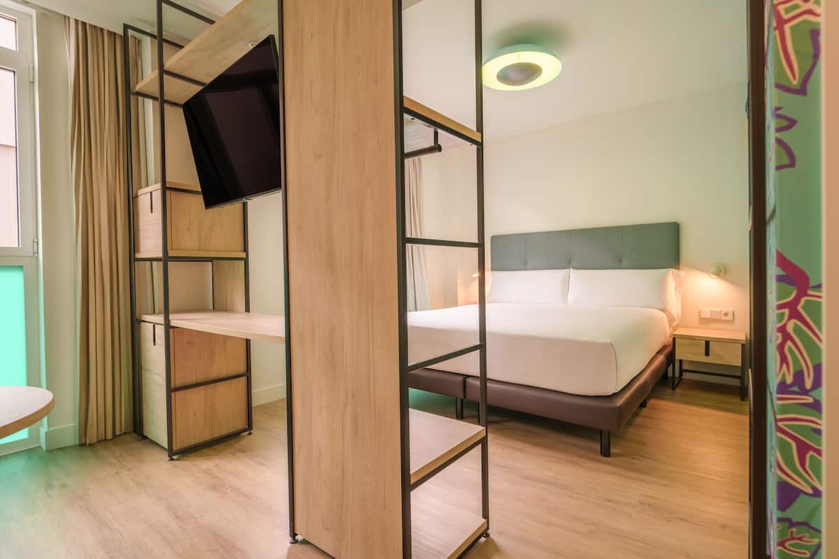 Quarto com cama beliche, escrivaninha com televisão e mesa de cabeceira.