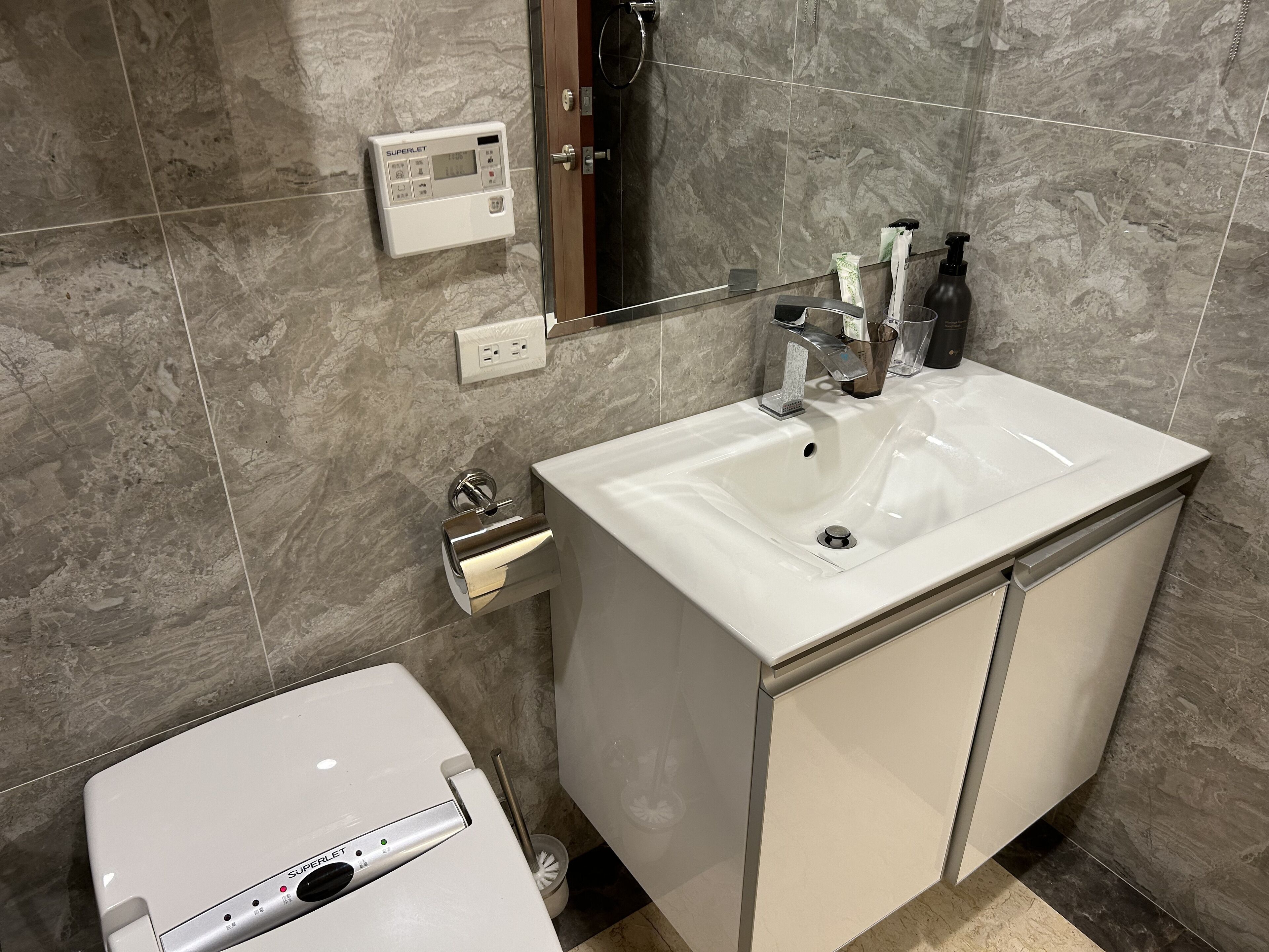 Uma casa de banho moderna com uma sanita branca, lavatório e zona de duche.