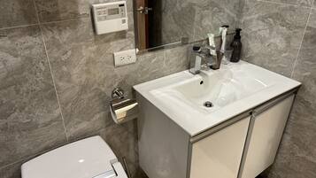 Uma casa de banho moderna com uma sanita branca, lavatório e zona de duche.
