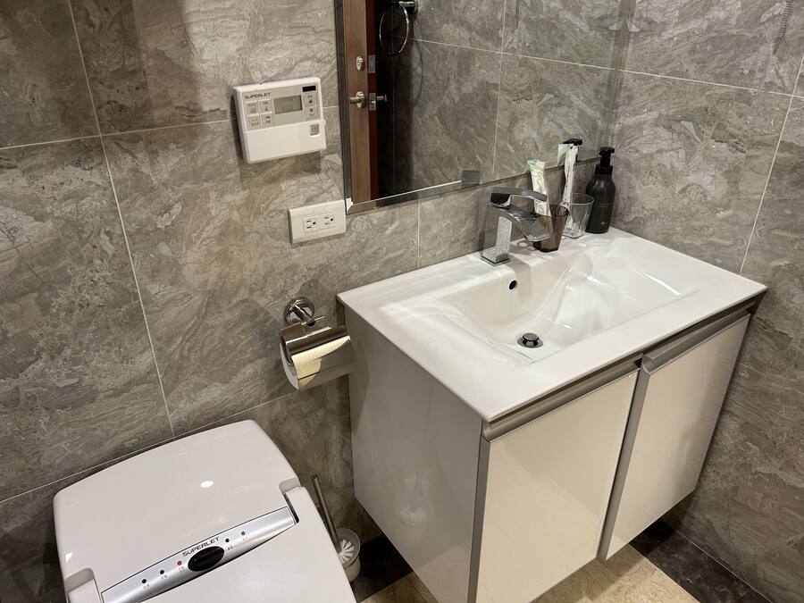 Uma casa de banho moderna com uma sanita branca, lavatório e zona de duche.