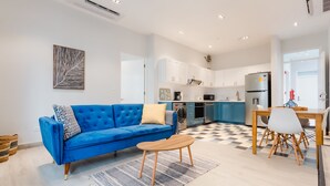 Uma sala de estar moderna com um sofá azul, uma mesa de centro de madeira e um tapete estampado.