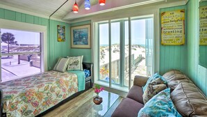 Quarto aconchegante com cama, sofá e uma grande janela com vista para a praia.
