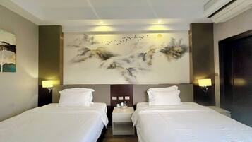 Quarto de hotel com duas camas, um grande mural na parede e uma mesa de cabeceira com abajur.