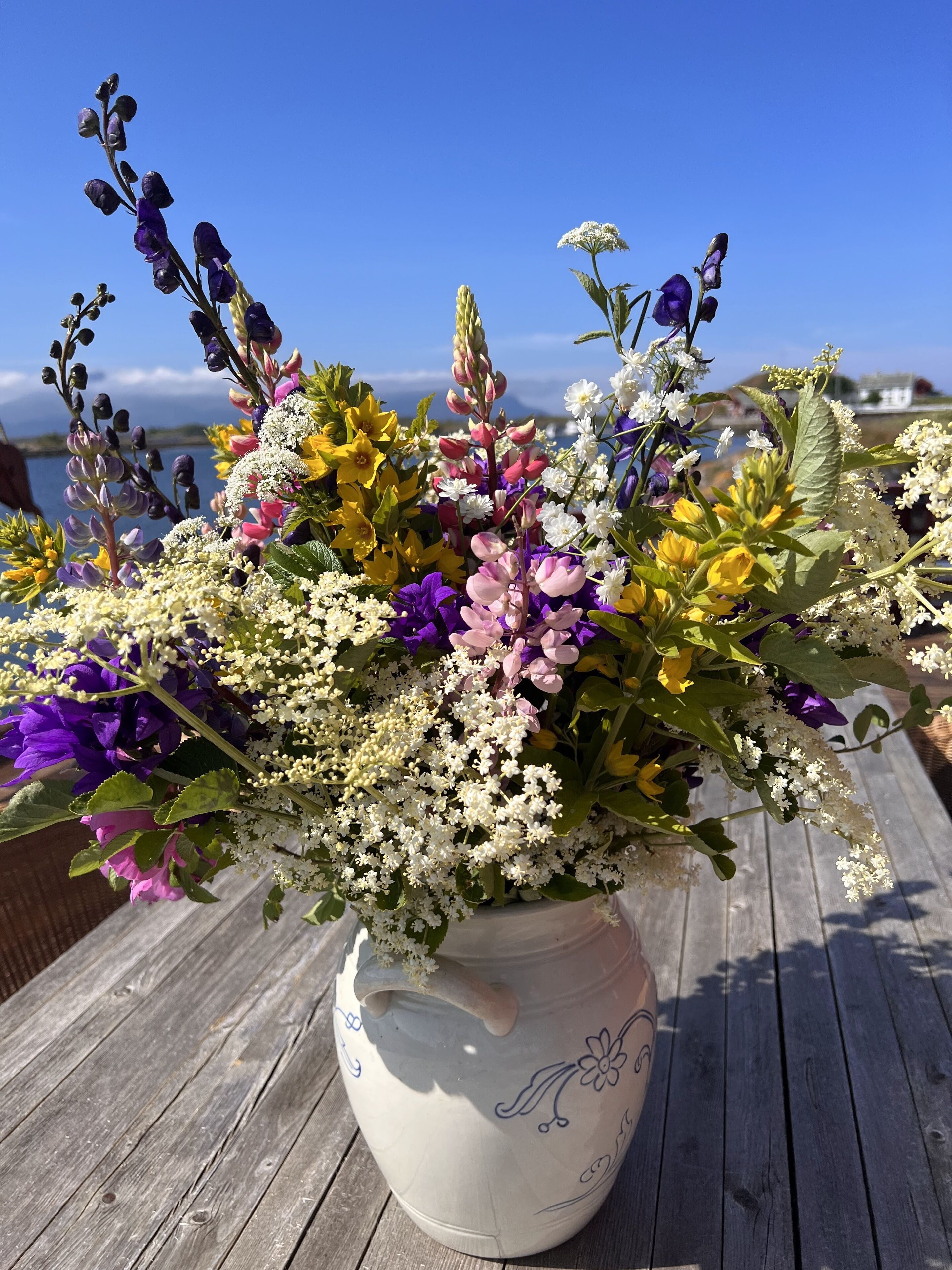 Um vaso de cerâmica branca com motivos florais sobre uma mesa de madeira.