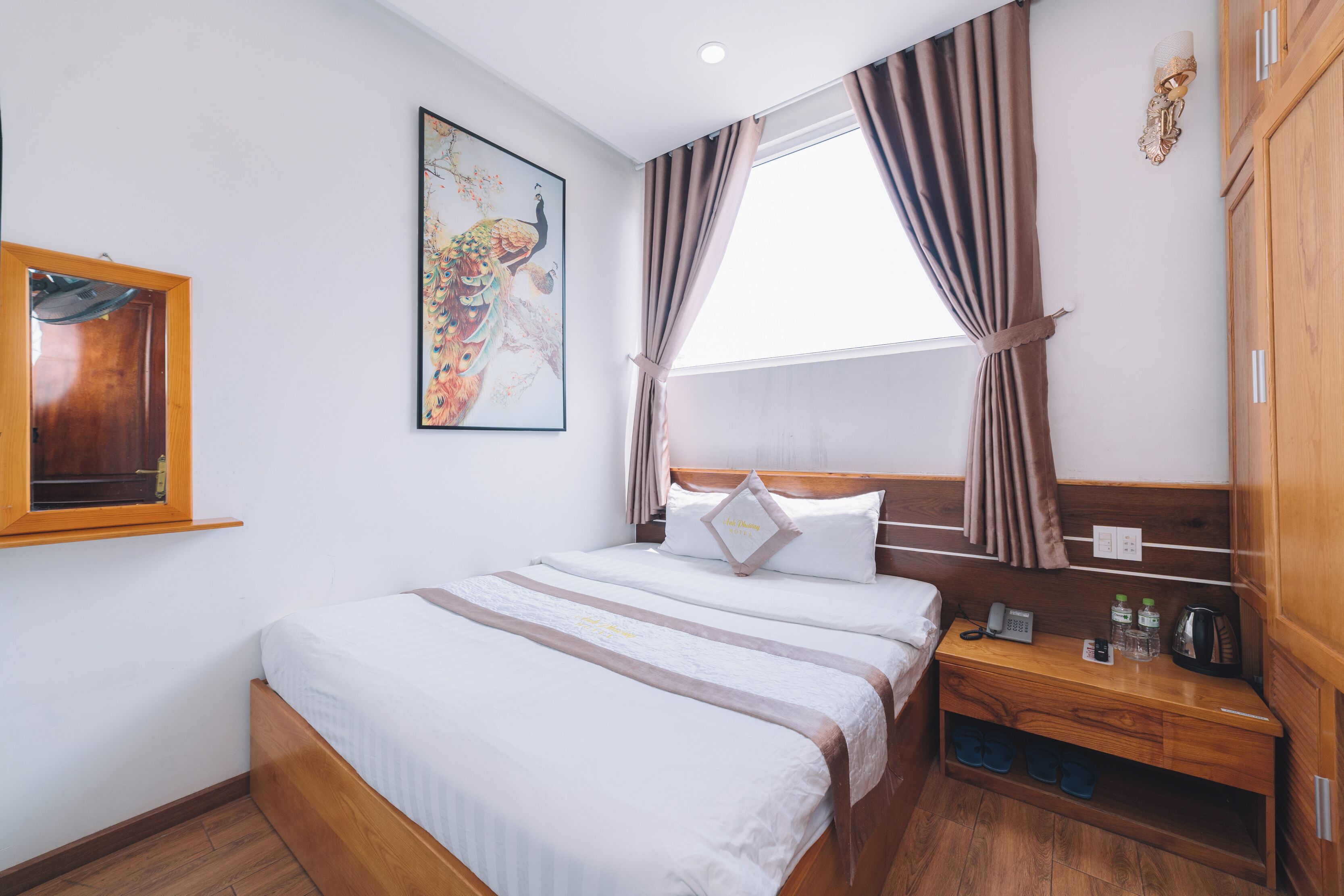 Quarto de hotel bem organizado, com cama, mesa de cabeceira e janela com cortinas.