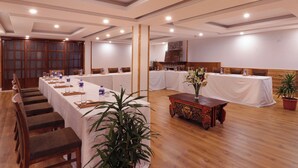 Uma sala de conferências com mesas compridas, cadeiras e um banco de madeira decorativo.