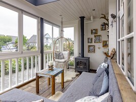 Um quarto aconchegante com sofá, cadeira suspensa, mesa e lareira.