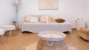Uma sala de estar moderna com uma mesa de centro redonda, um sofá com almofadas estampadas e uma obra de arte na parede.