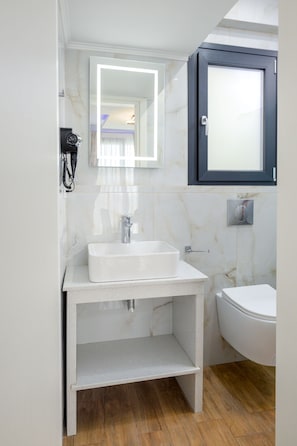 Uma casa de banho moderna com uma sanita, um lavatório branco e um espelho.