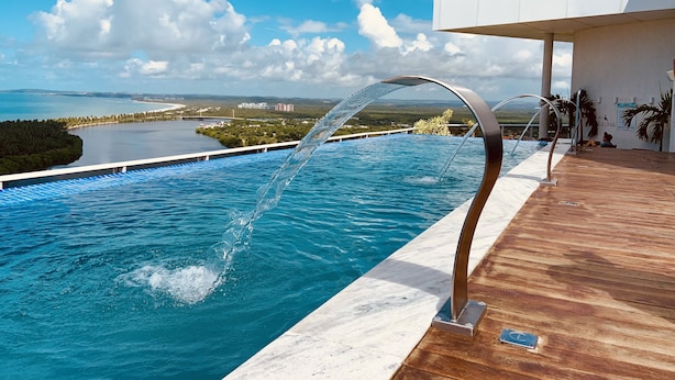 Piscina com um elemento aquático, deck de madeira e vista da paisagem ao redor.