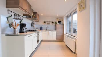 Uma cozinha moderna com armários brancos, eletrodomésticos de aço inoxidável e uma janela que traz luz natural.