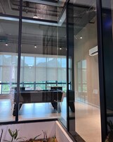 Um espaço moderno em ambiente interno com mesa de bilhar, janelas amplas e vista para o verde lá fora.