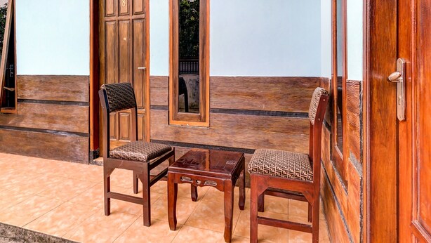 Uma mesa de madeira e duas cadeiras em um quarto com chão de azulejos e porta de madeira.