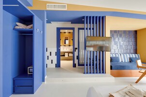 Quarto moderno com cama, televisão e banheiro visível por uma porta aberta.