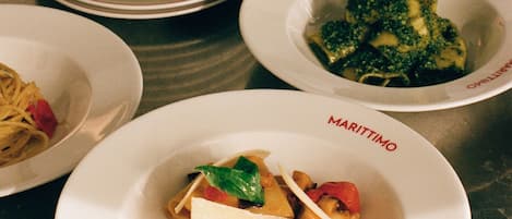 Uma mesa com vários pratos brancos com a inscrição 'MARITTIMO', contendo diferentes pratos.