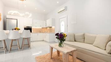 Uma sala de estar moderna com um sofá, uma mesa de centro e um espaço de jantar com cadeiras.