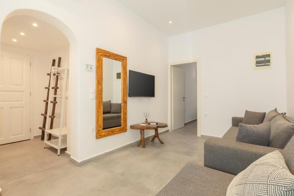 Uma sala de estar com sofá, escada de madeira, espelho e TV de tela plana fixada na parede.