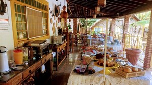 Um café com decoração rústica, apresentando um balcão comprido com diversos alimentos e uma mesa com doces.