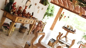 Uma sala de jantar com mobiliário de madeira, piso ladrilhado e diversos objetos decorativos nas paredes.