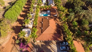 Vista aérea de um resort com piscina, palmeiras e um edifício com telhado vermelho.