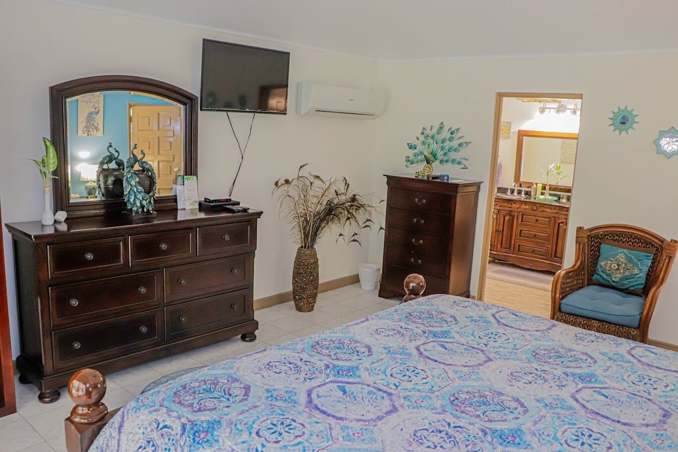 Quarto com cama grande, cômoda, televisão e espelho.