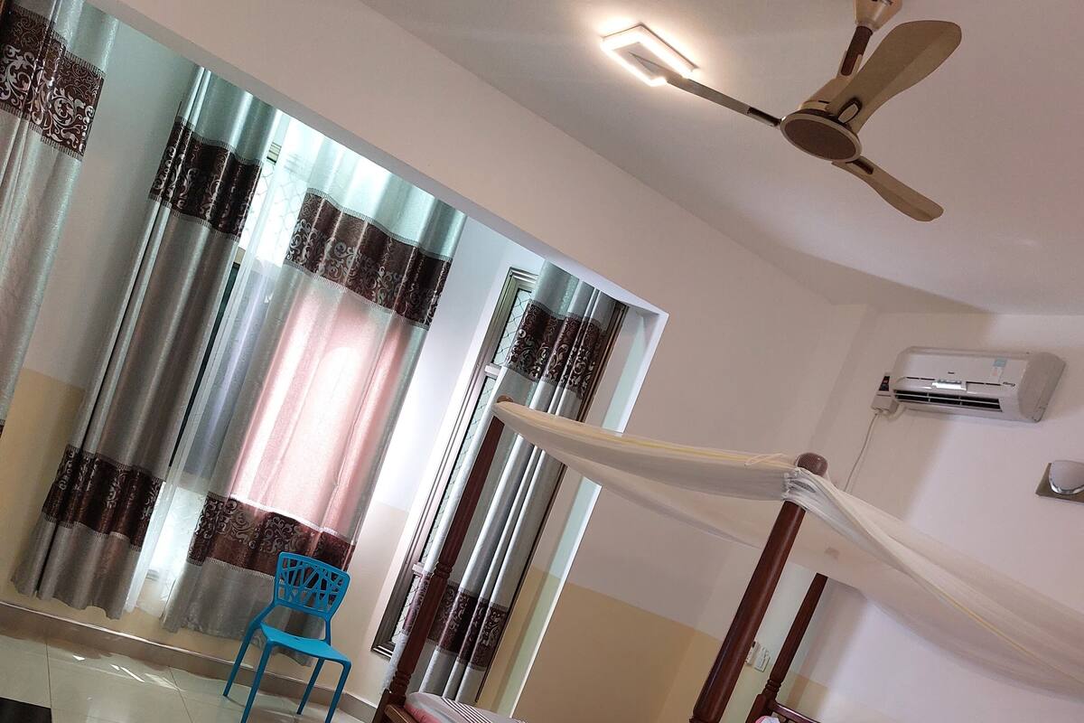 Um quarto com uma cama de dossel, um ventilador de teto e um tapete vermelho.