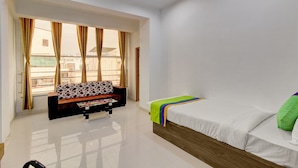 Quarto com cama, sofá e janela com cortinas.