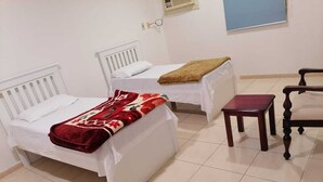 Quarto com duas camas de solteiro, uma mesinha de madeira e uma cadeira.
