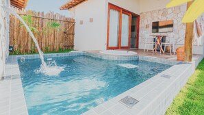 Piscina com muro de pedra e cerca de madeira ao fundo.