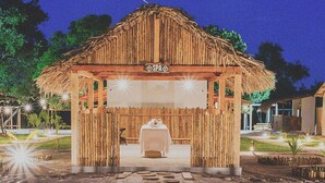 Uma construção com telhado de palha, com uma placa que diz "SPA" e um banco em frente.