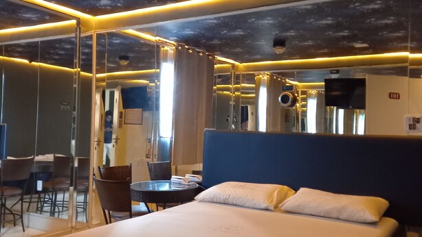 Quarto de hotel com cama, escrivaninha e cadeira.