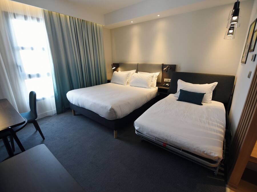 Quarto de hotel com duas camas, uma mesa e uma cadeira.