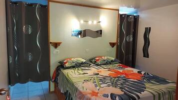 Quarto com cama, espelho e luminária fixada na parede.
