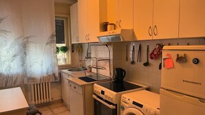 Cozinha compacta com máquina de lavar, fogão e pia.