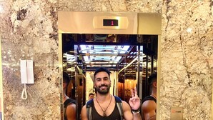 Um homem em pé num elevador, com um visor digital a mostrar o número 1.