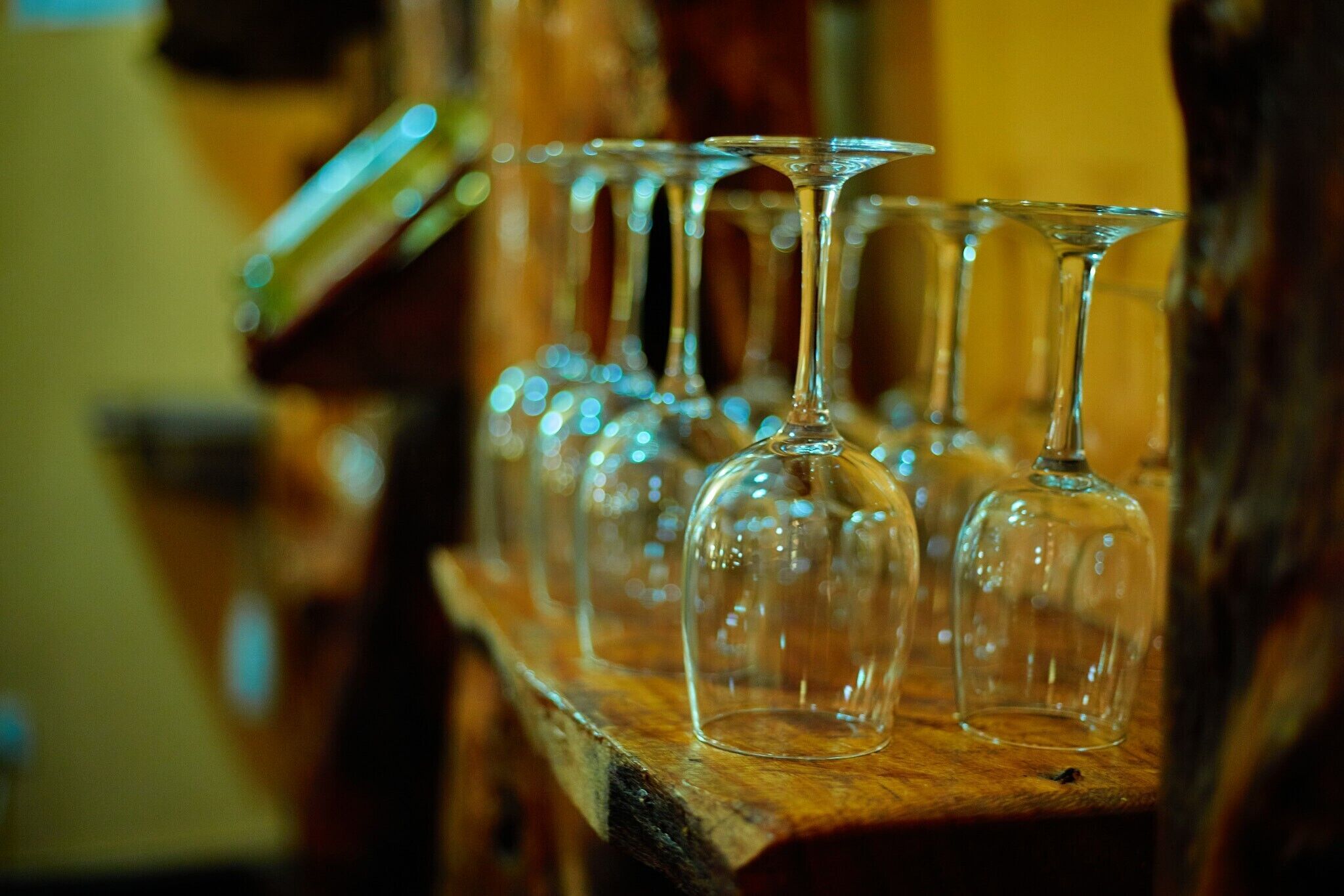Vários copos de vinho vazios em um balcão de madeira.