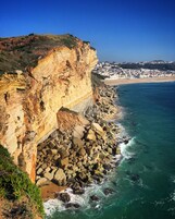 Um penhasco costeiro com uma linha de costa rochosa e ondas a quebrar.