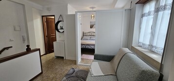 Quarto compacto com uma cama, sofá, mesa pequena e guarda-roupa.