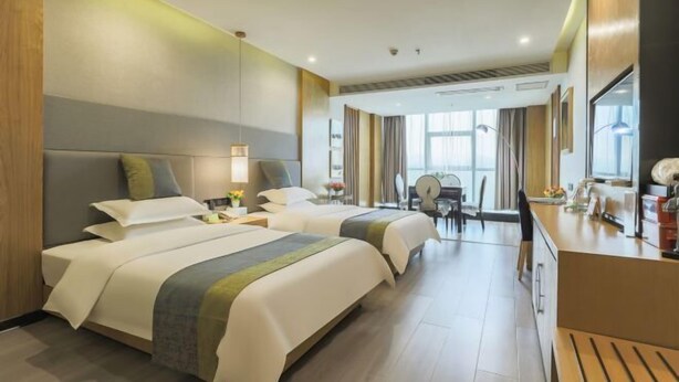 Quarto de hotel com duas camas, uma escrivaninha e um espaço de refeições.