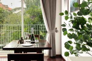 Mesa de jantar posta com garrafa, copos e cardápio, com vista para um jardim exuberante.