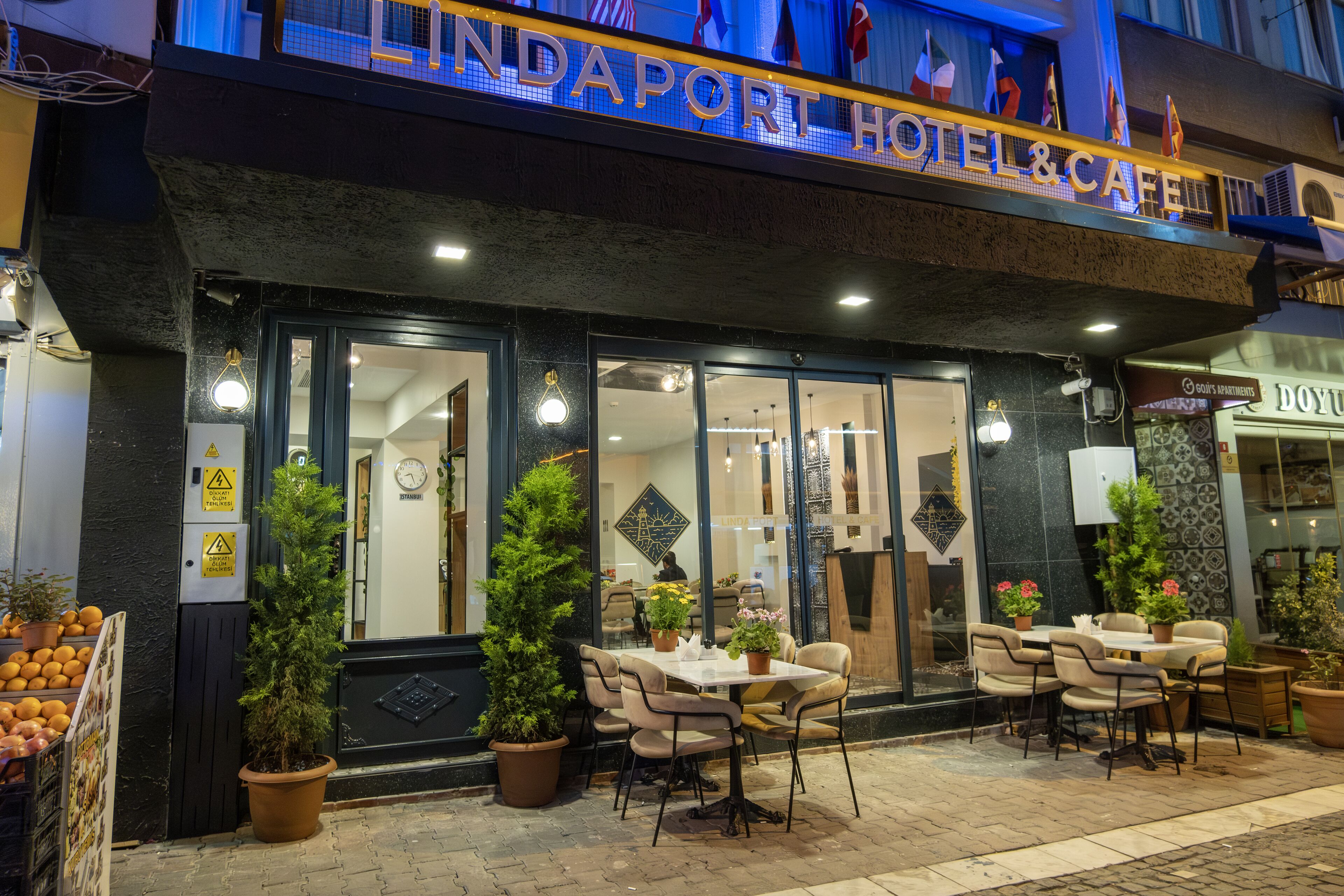 Exterior do Hotel & Café Hindaport com área de estar externa e plantas em vasos.