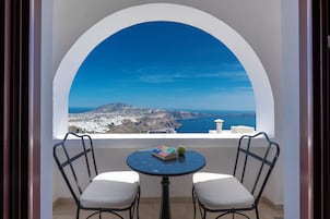 Varanda com duas cadeiras, uma mesa e vista para a paisagem costeira.