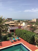 Uma área de piscina com espreguiçadeiras e vista para o mar.