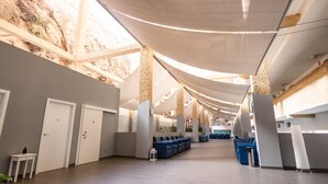 Um hall espaçoso com teto alto, áreas de estar e vista para uma paisagem rochosa.