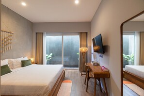 Quarto de hotel moderno com uma cama grande, uma escrivaninha, uma TV e uma porta de vidro deslizante para o exterior.