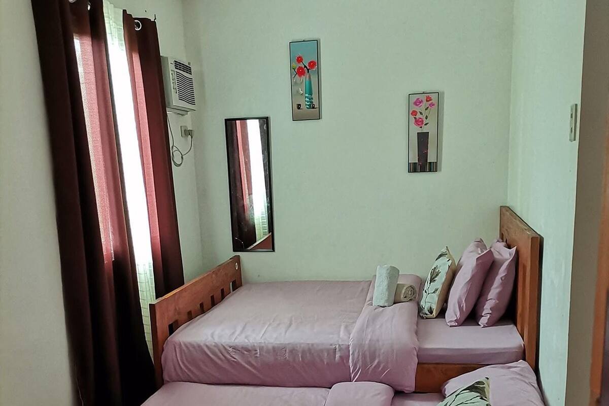 Quarto com duas camas, cada uma com cabeceira de madeira, e um espelho grande na parede.