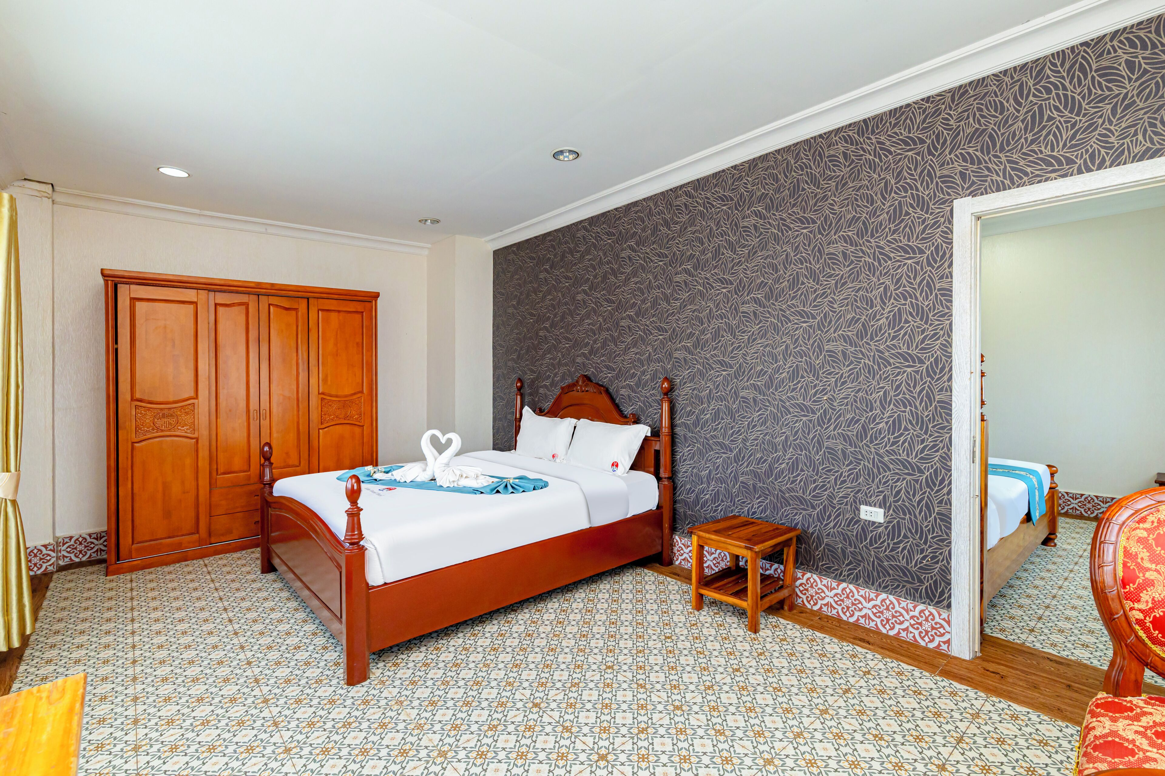 Quarto de hotel com cama de madeira, uma pequena mesa de cabeceira, um guarda-roupa e parede com padrão.