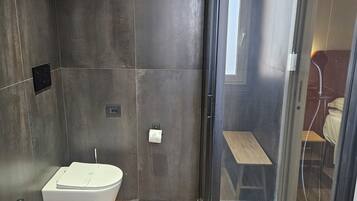 Uma casa de banho moderna com sanita, lavatório e área de duche.