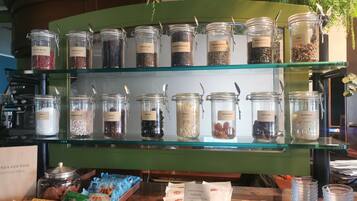 Uma área de buffet com diversos alimentos e condimentos expostos em recipientes de vidro.
