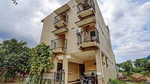 Edifício de vários andares com sacadas, entrada coberta e uma motocicleta estacionada.
